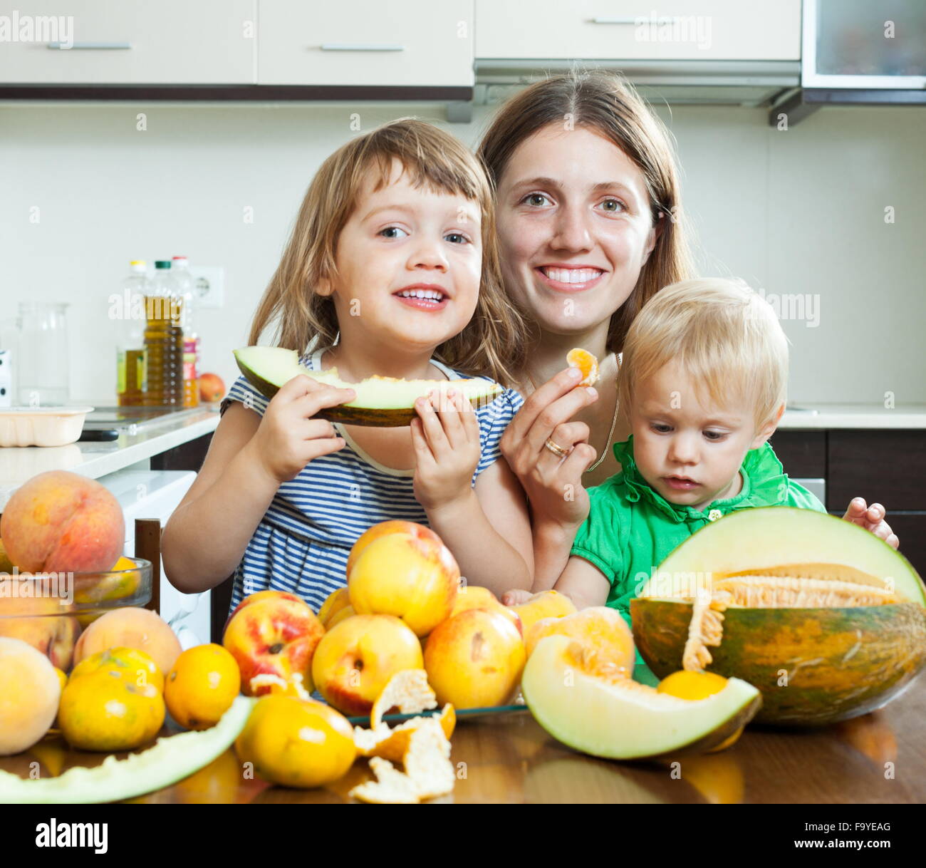 Happy family eating melon and other fruits over table at home interior ...
