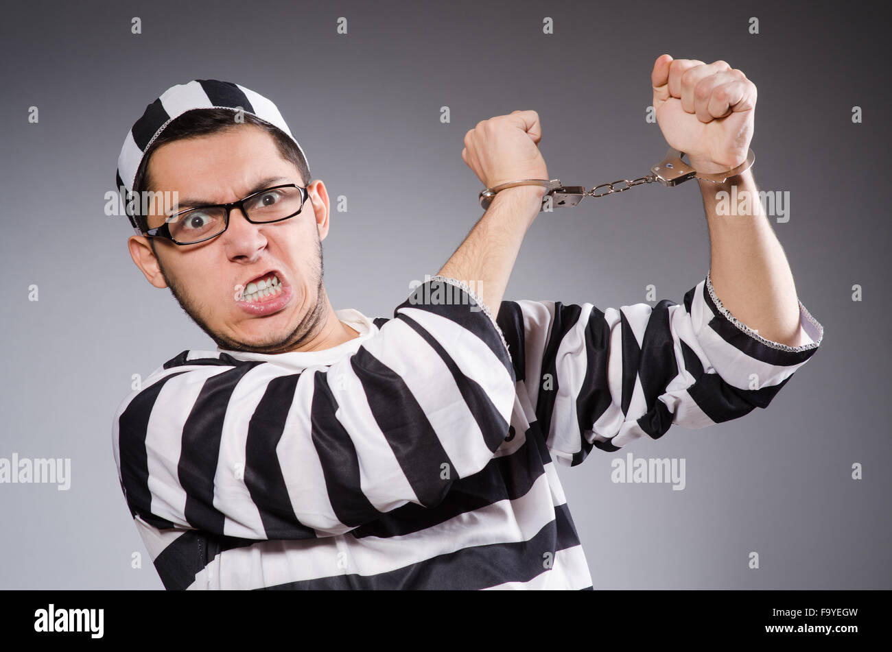 Young prisoner in handcuffs against gray Stock Photo - Alamy