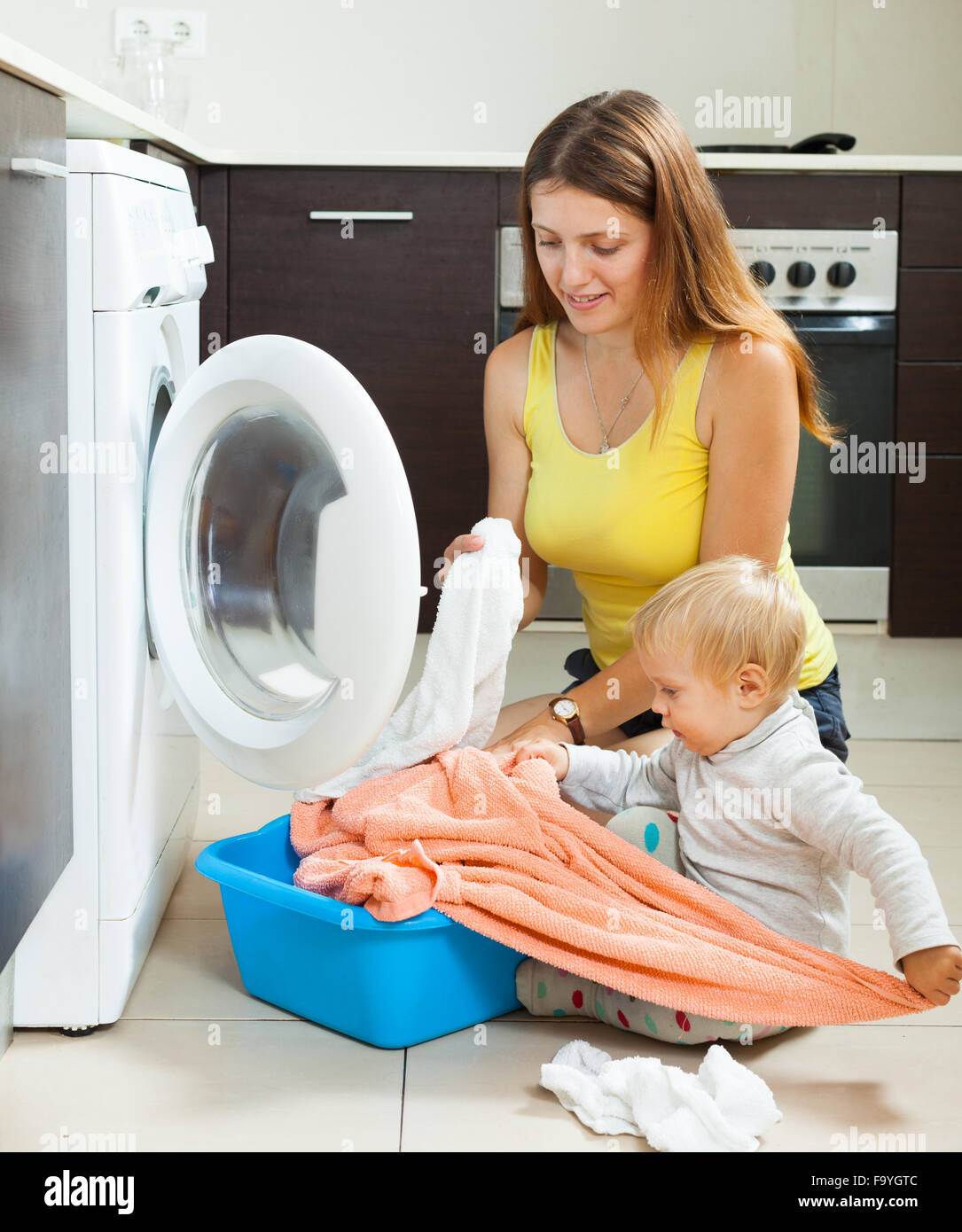 Family woman putting clothes in to washing machine at home Stock Photo ...