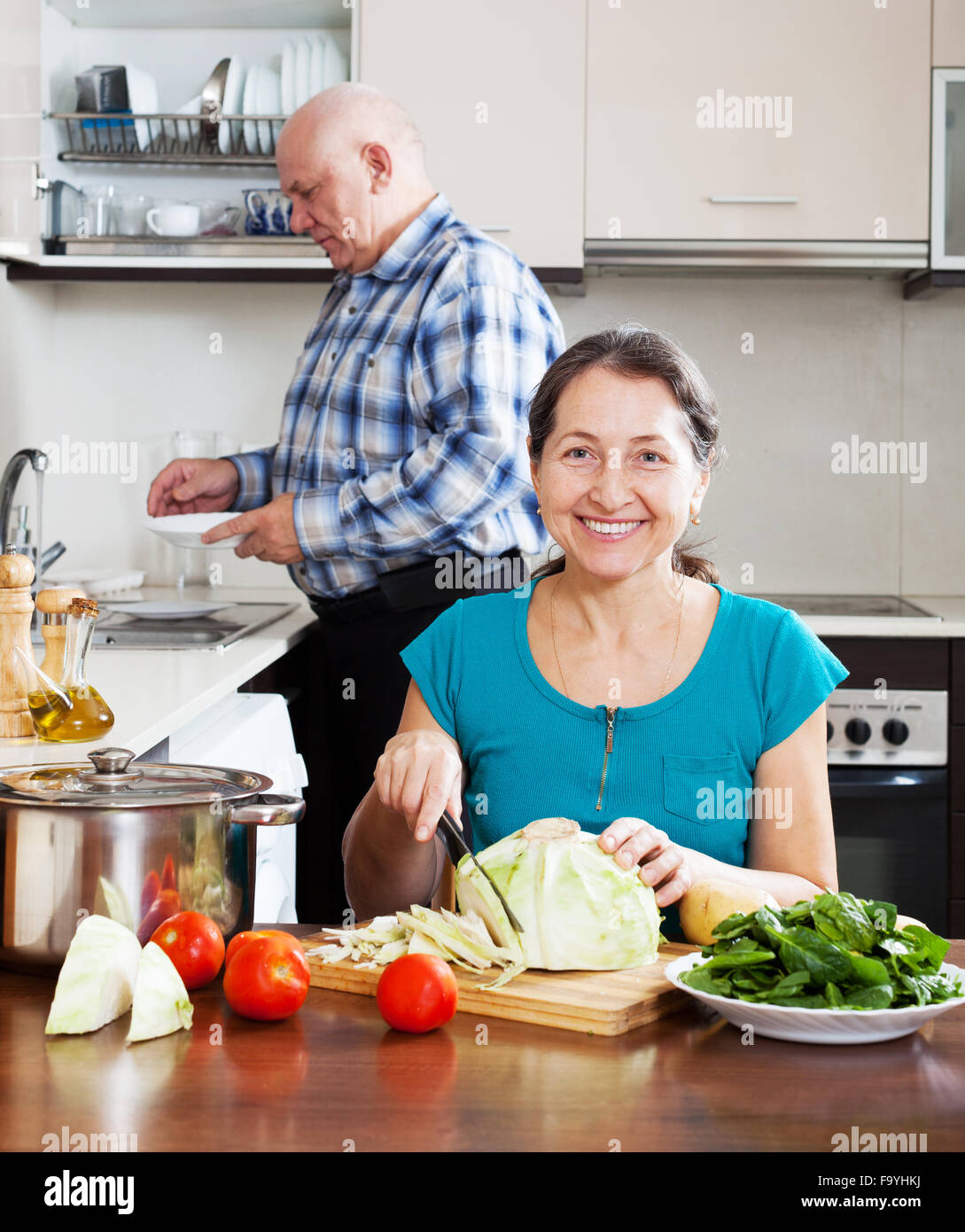 Happy mature woman cooking with husband in domestic kitchen Stock Photo ...
