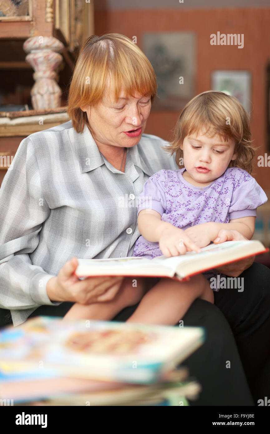 grandmother and child reading book together on couch in home Stock ...