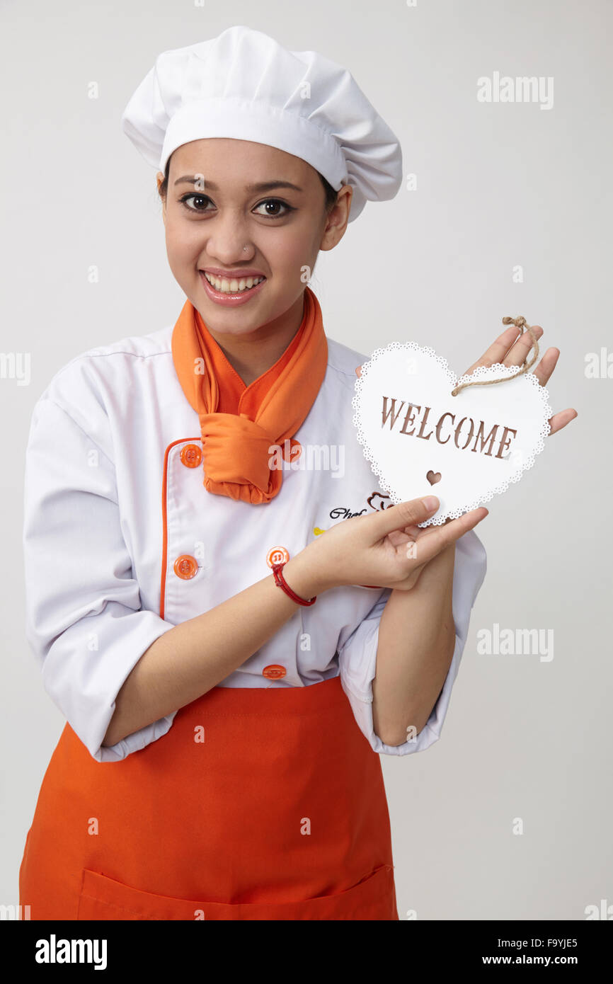 Indian woman with chef uniform holding a welcome signage Stock Photo ...