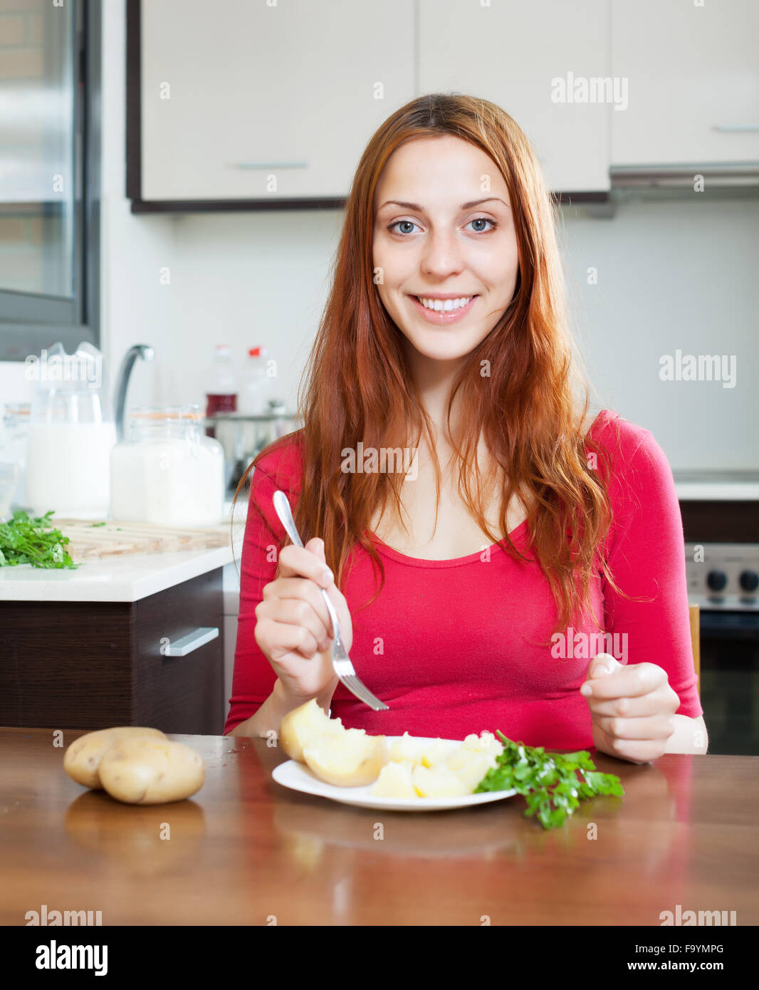 woman in red eating jacket potatoes at home interior Stock Photo - Alamy