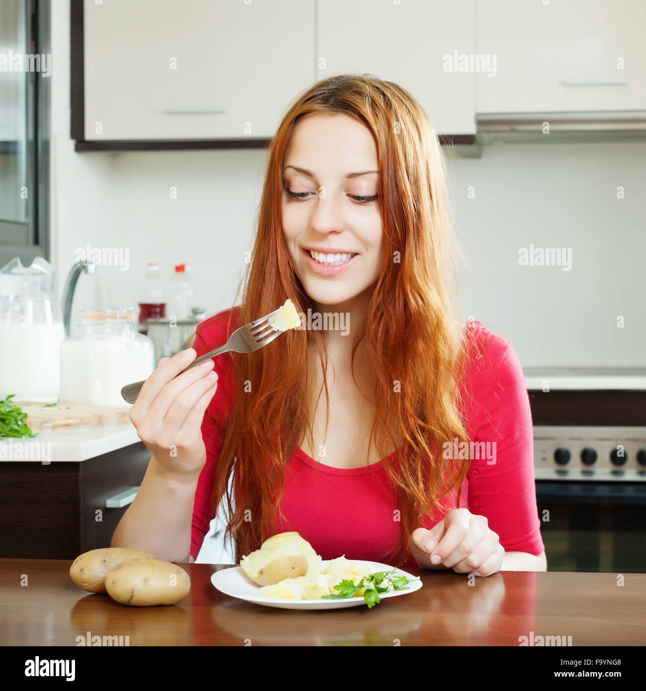 Casual positive girl eating potatoes at home interior Stock Photo - Alamy