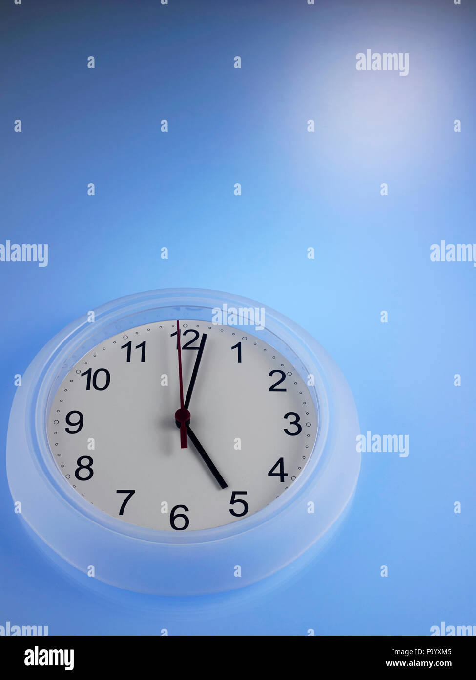 Clock showing 5 o'clock on a blue wall Stock Photo - Alamy