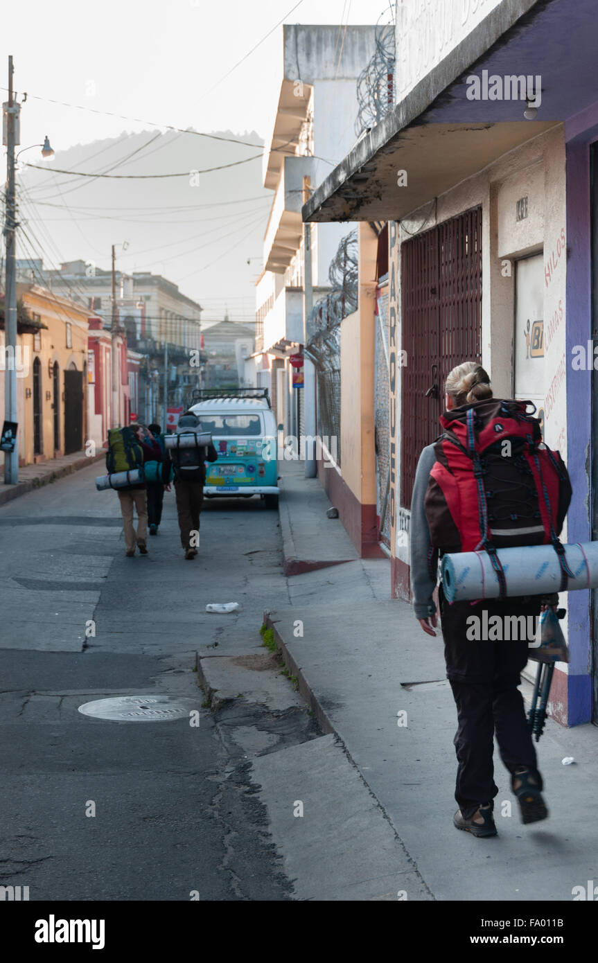 Hikers with backpacks walking along the street between houses Stock ...