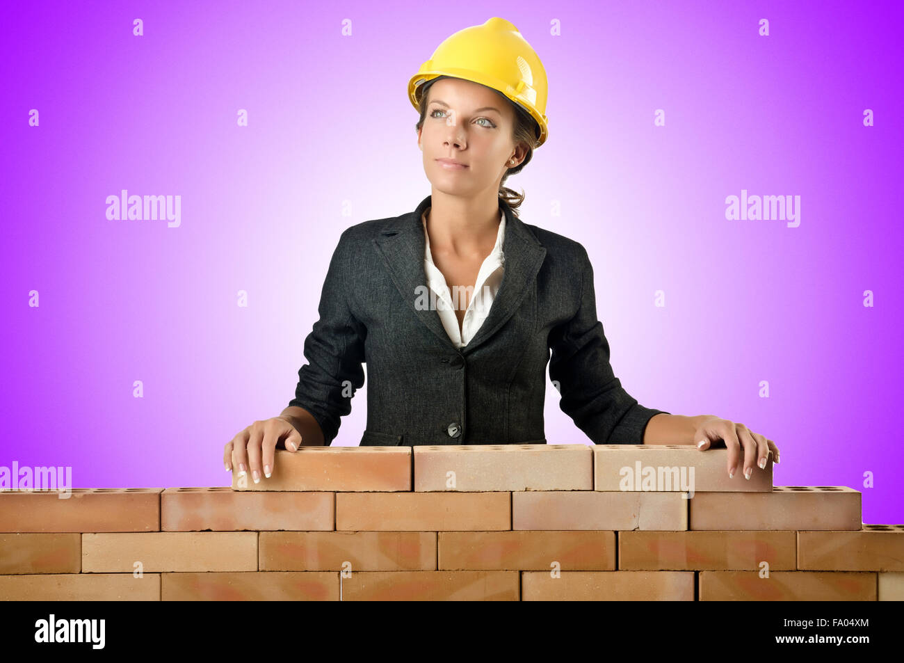 Young female builder near brick wall Stock Photo - Alamy