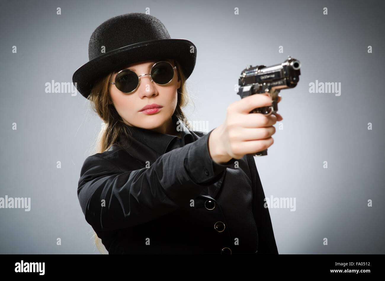 Female spy with weapon against gray Stock Photo - Alamy
