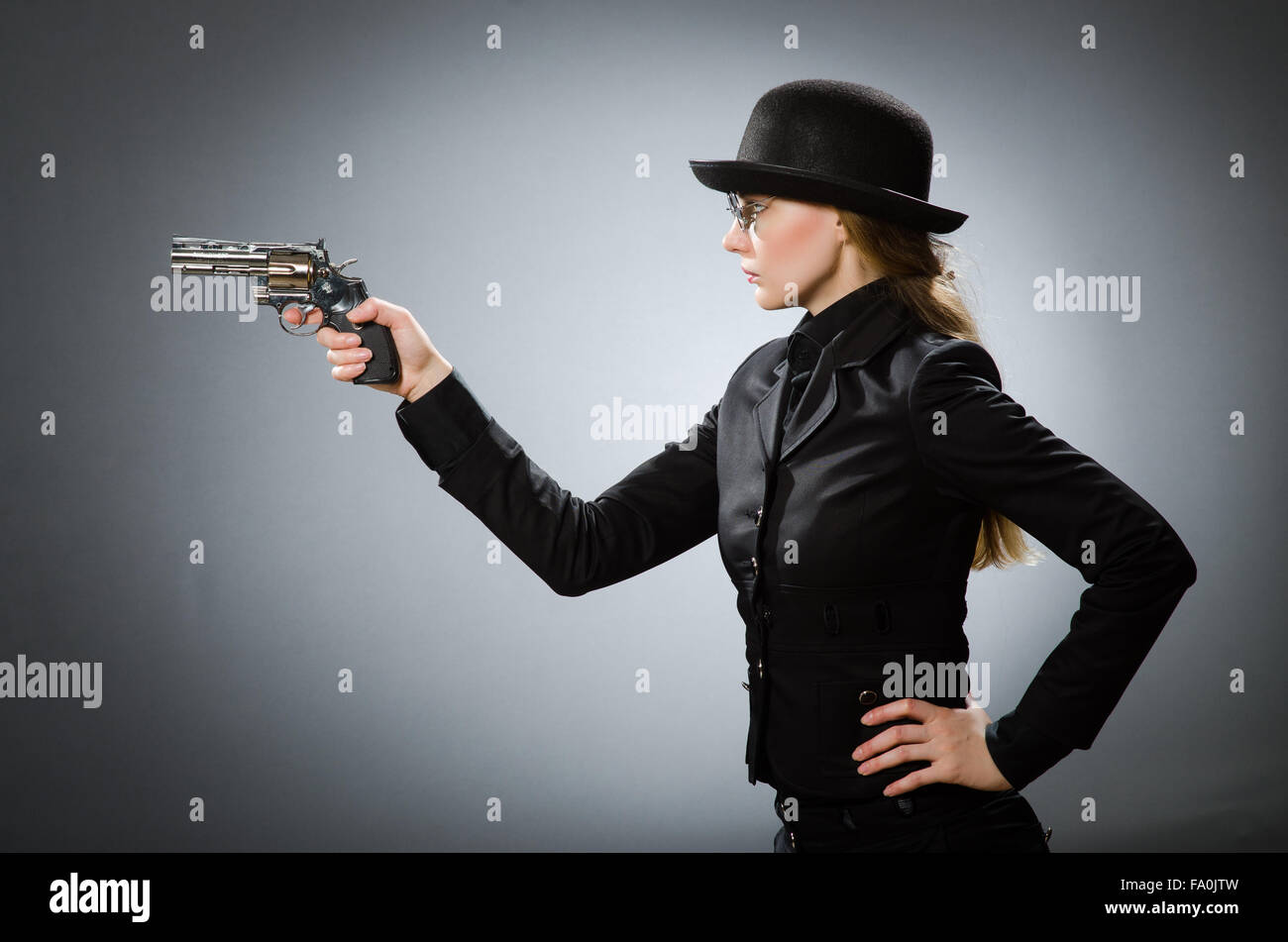 Female spy with weapon against gray Stock Photo - Alamy
