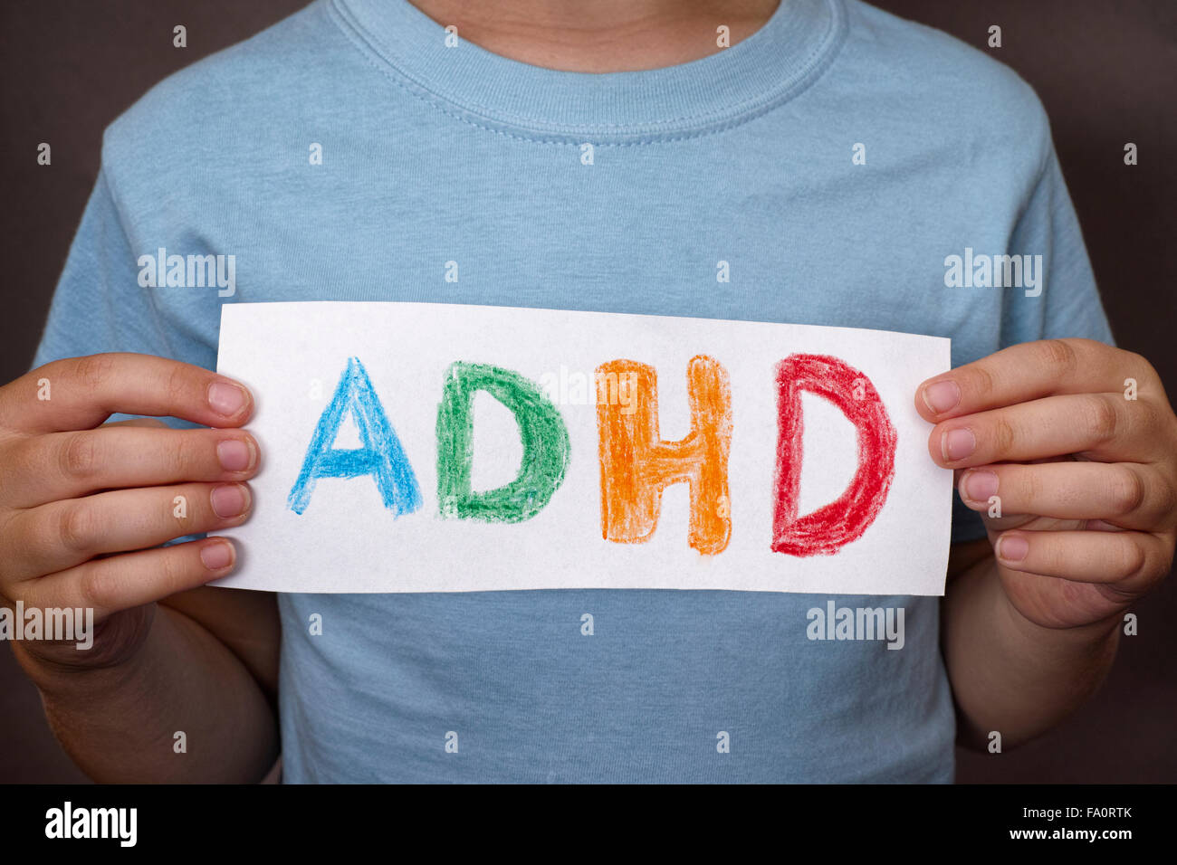 Young boy holds ADHD text written on sheet of paper. ADHD is Attention ...