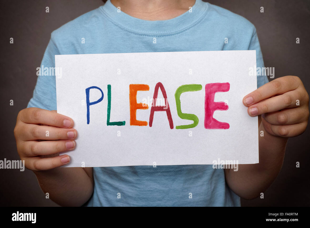 Young boy holds paper note with word Please. Close up Stock Photo - Alamy