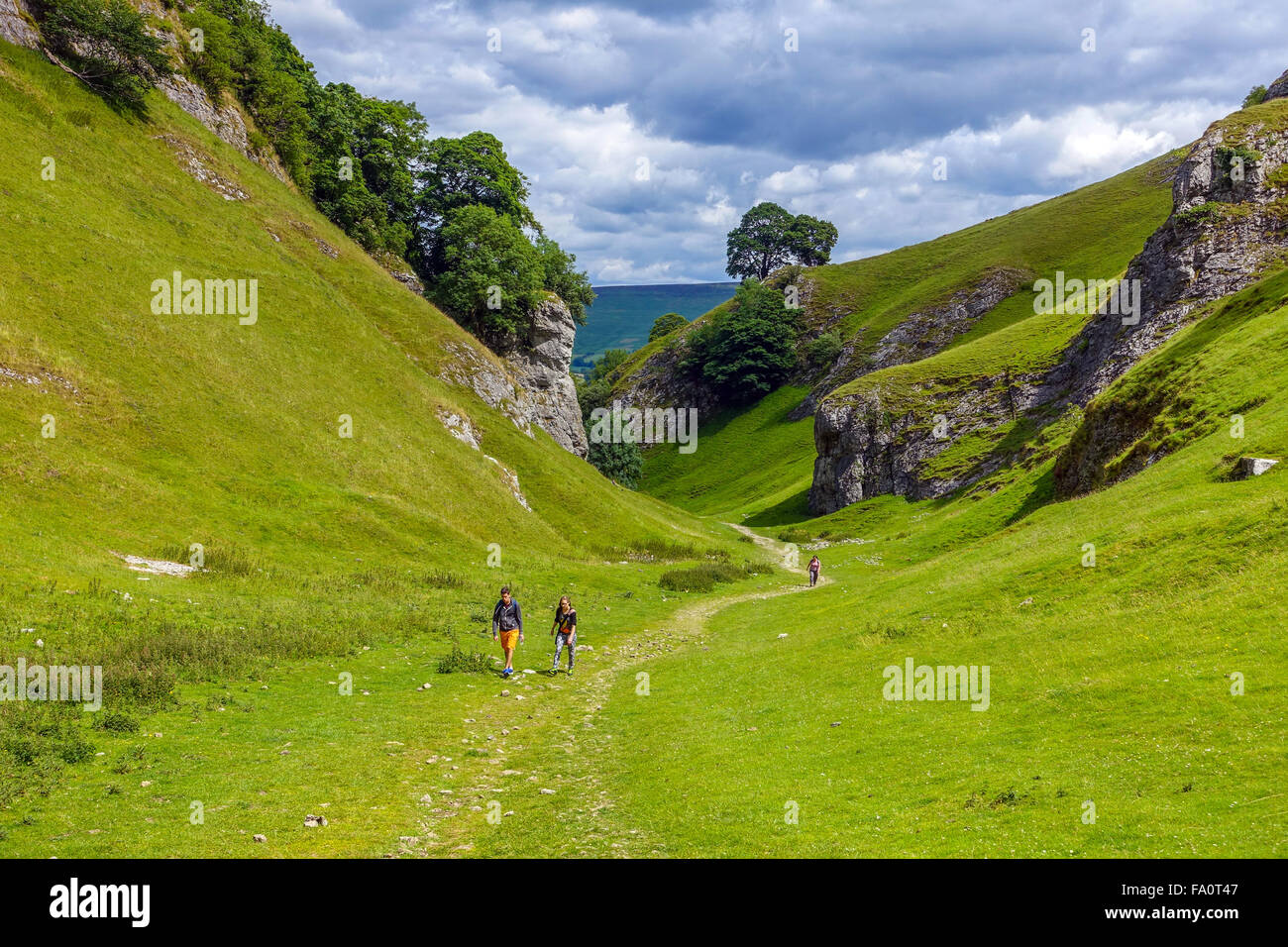 Three walkers hikers in Cavedale with Pevril Castle, Castleton Stock ...