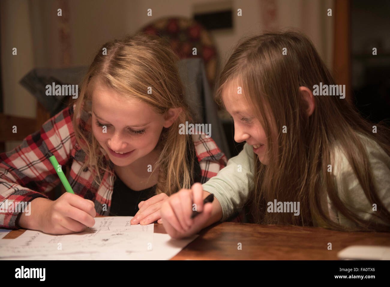 Two girls having fun drawing at a table Stock Photo - Alamy