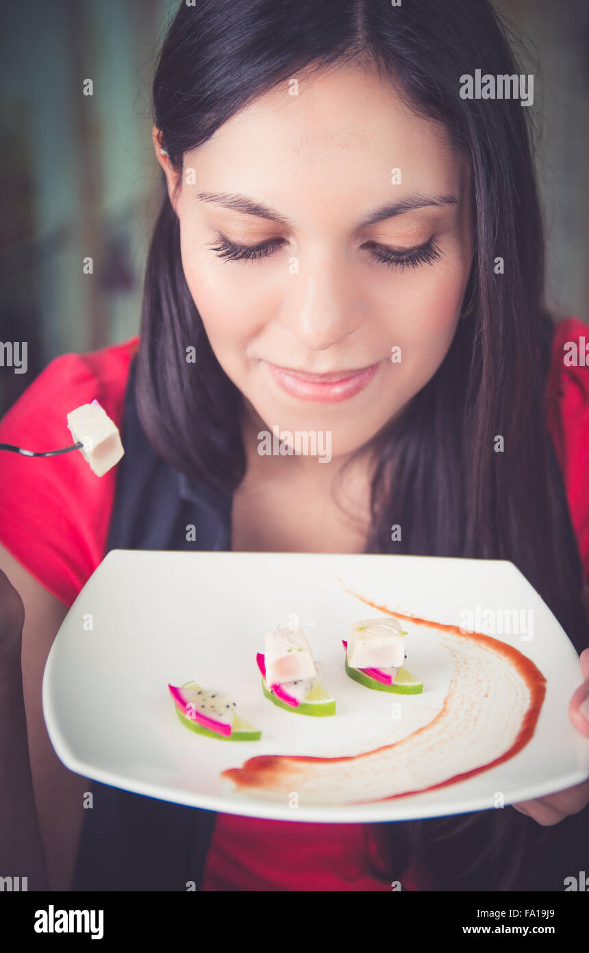 Beautiful young woman enjoying a delicious seafood plate with tuna ...