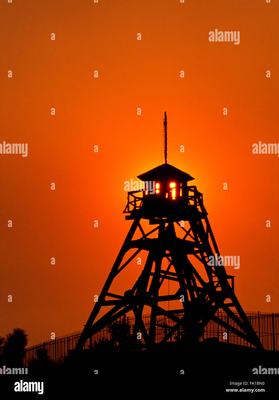 rising sun glowing in a smoky sky behind the historic fire tower in ...