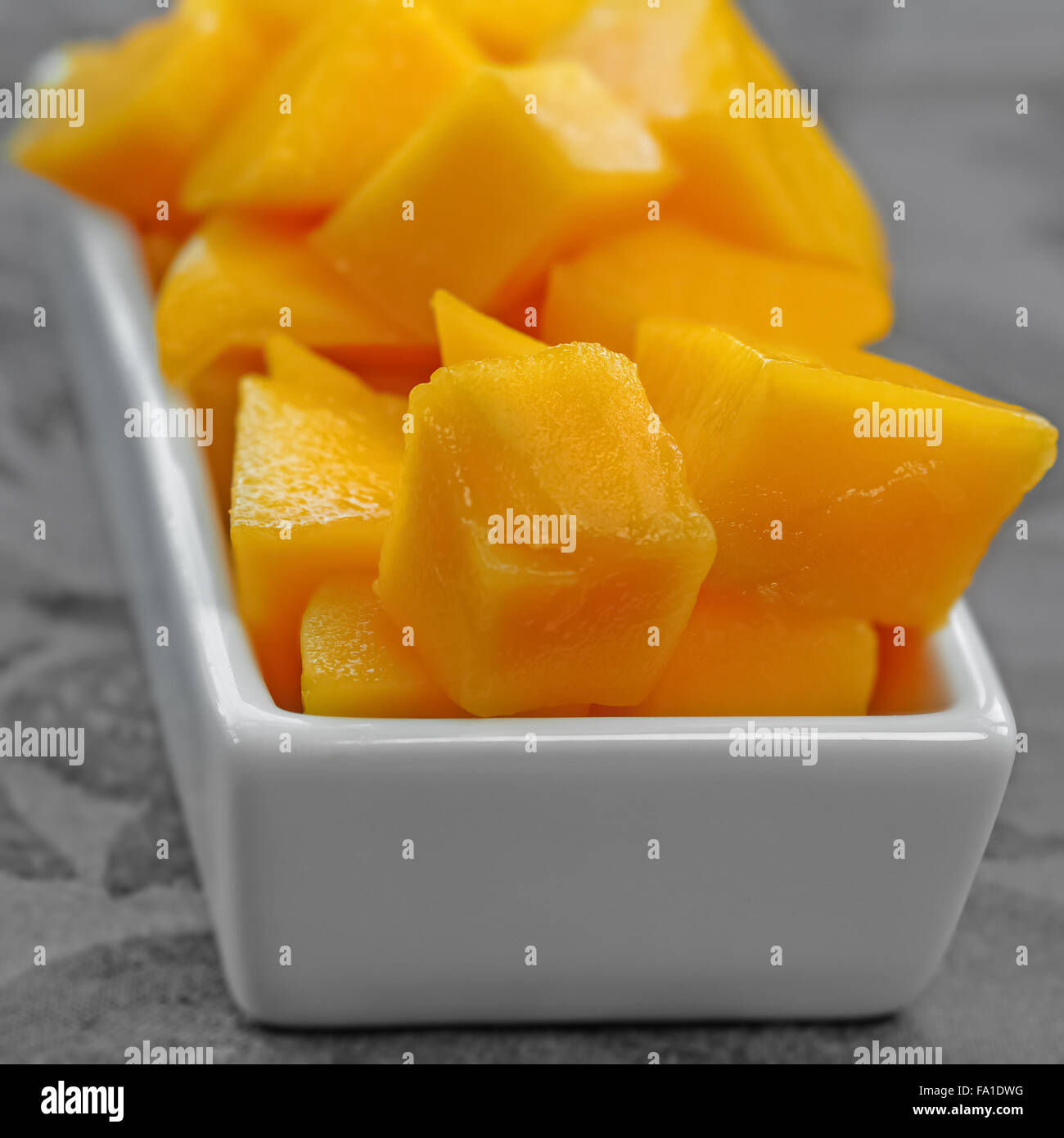 Diced mango cubes placed and served on a white dish square composition ...