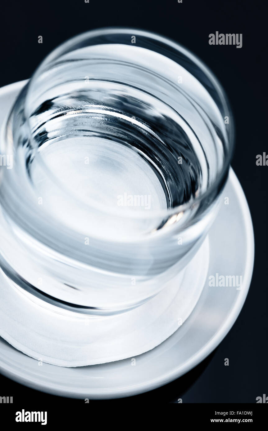 Single glass of clean clear drinking water tilted tilt view close up ...