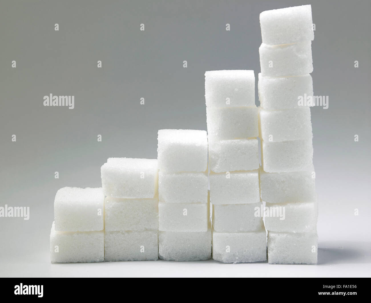 Ascending stacks of sugar cubes over gray background. This in a concept ...