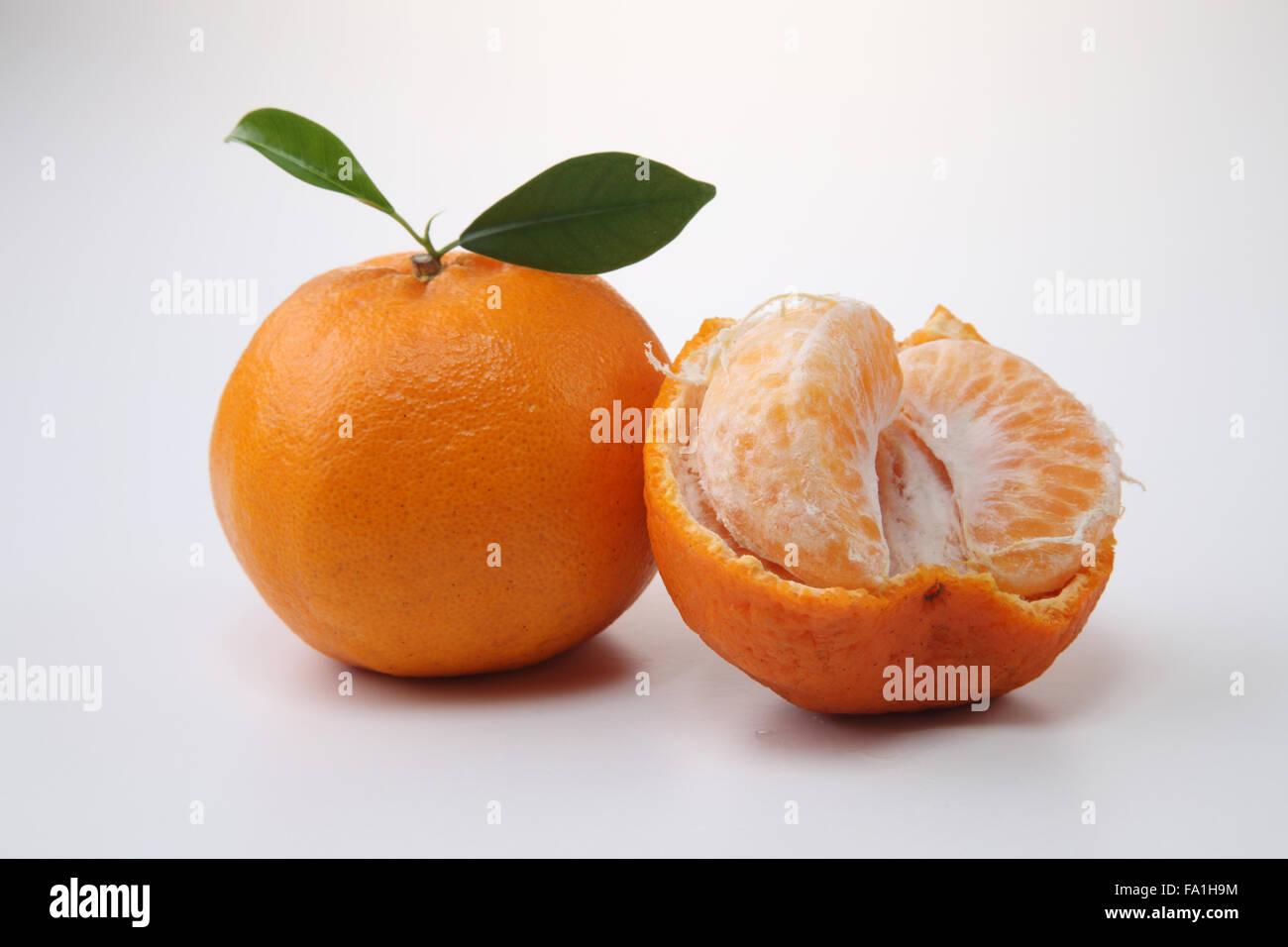 One mandarin orange and one half open Stock Photo - Alamy