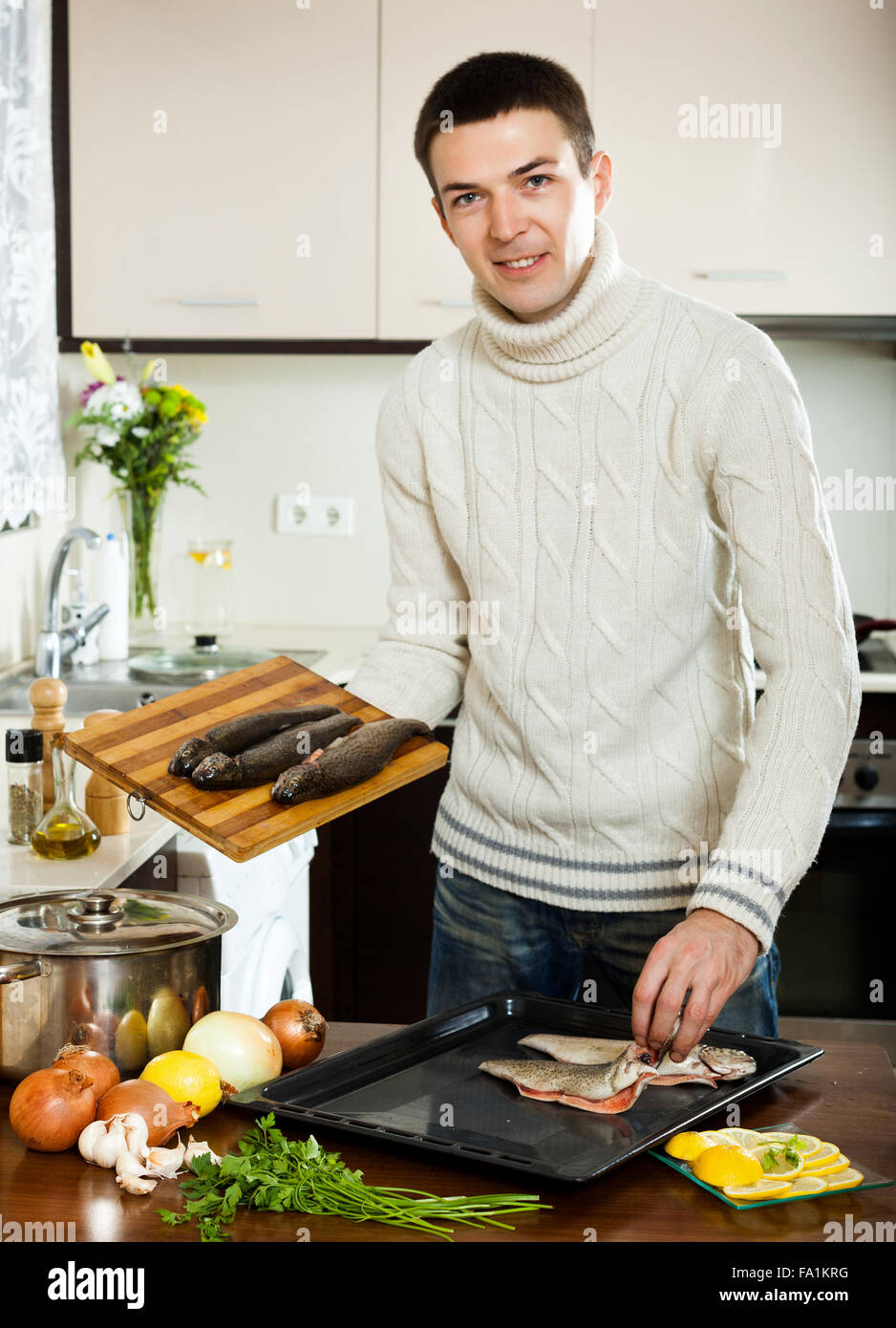 Smiling guy cooking trout fish in frying pan Stock Photo - Alamy