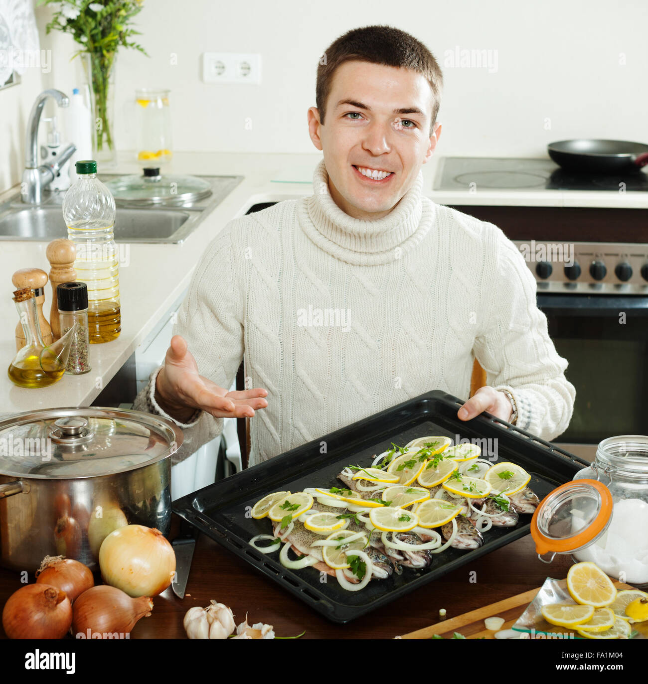 Handsome man with raw fish on roasting pan at kitchen Stock Photo - Alamy