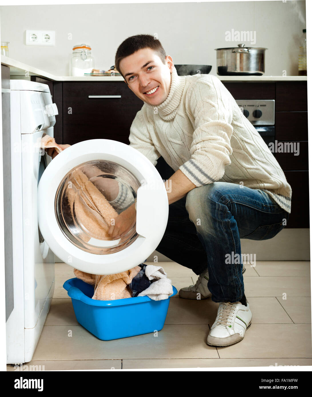 Smiling guy using washing machine at home Stock Photo - Alamy