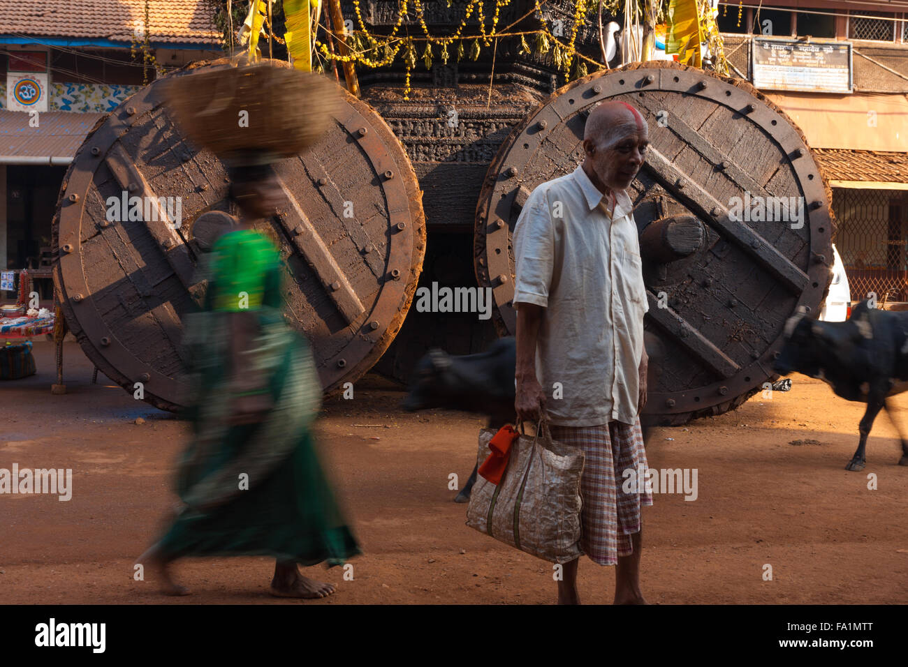 A hindu man with painted face standing in front of a large chariot ...