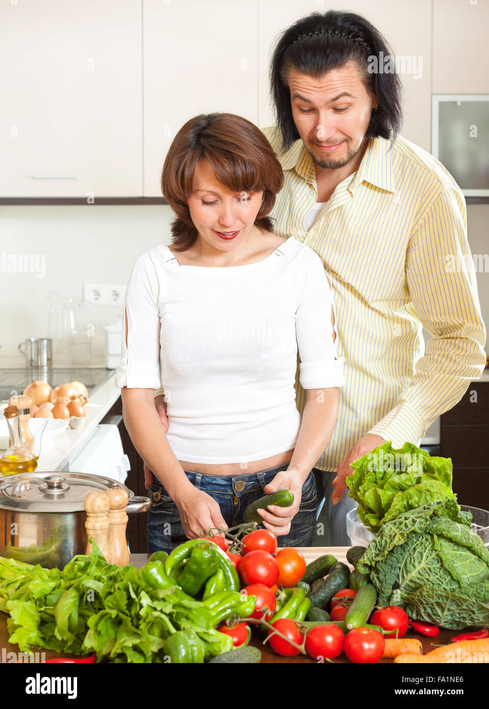 Couple with fresh vegetables and greens in home kitchen Stock Photo - Alamy