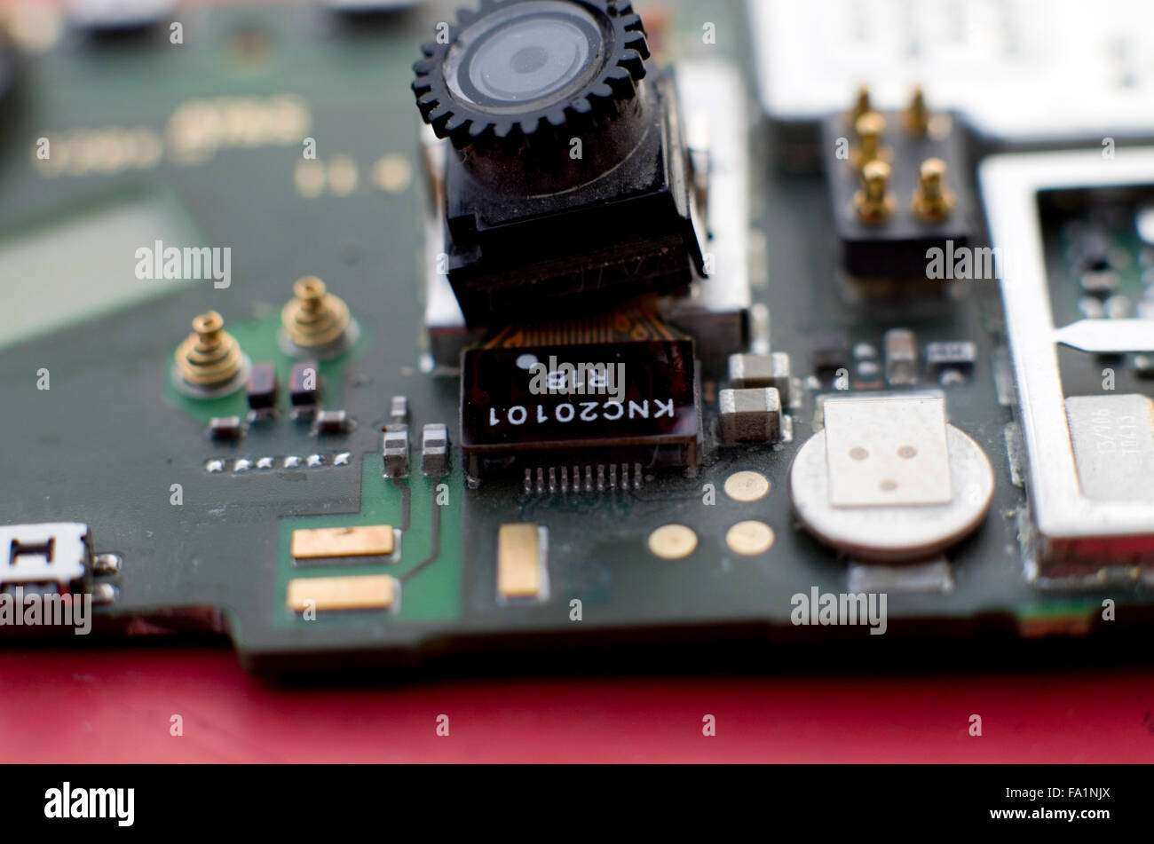 A pile of broken pieces of mobile phones and phone batteries on a red ...