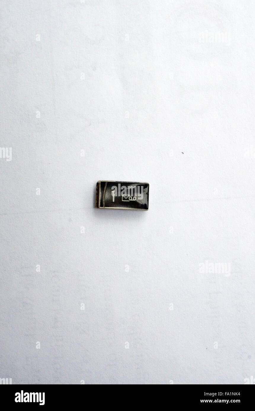 Broken number 1 key from a mobile phone laying on a white background ...