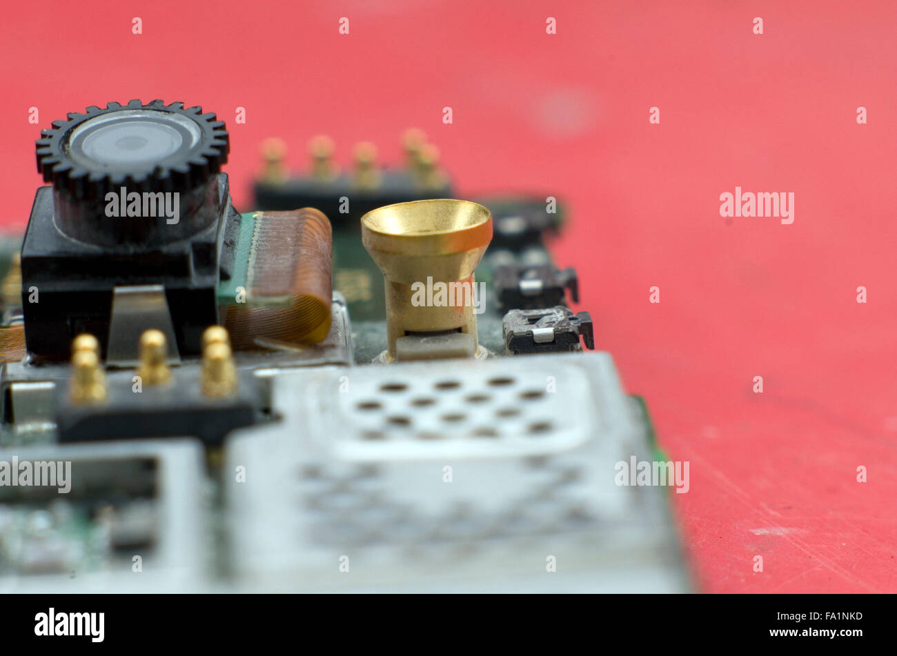 A pile of broken pieces of mobile phones and phone batteries on a red ...