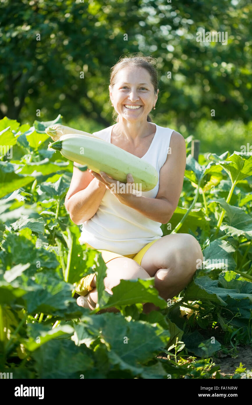 Happy woman picking vegetable marrow in field Stock Photo - Alamy