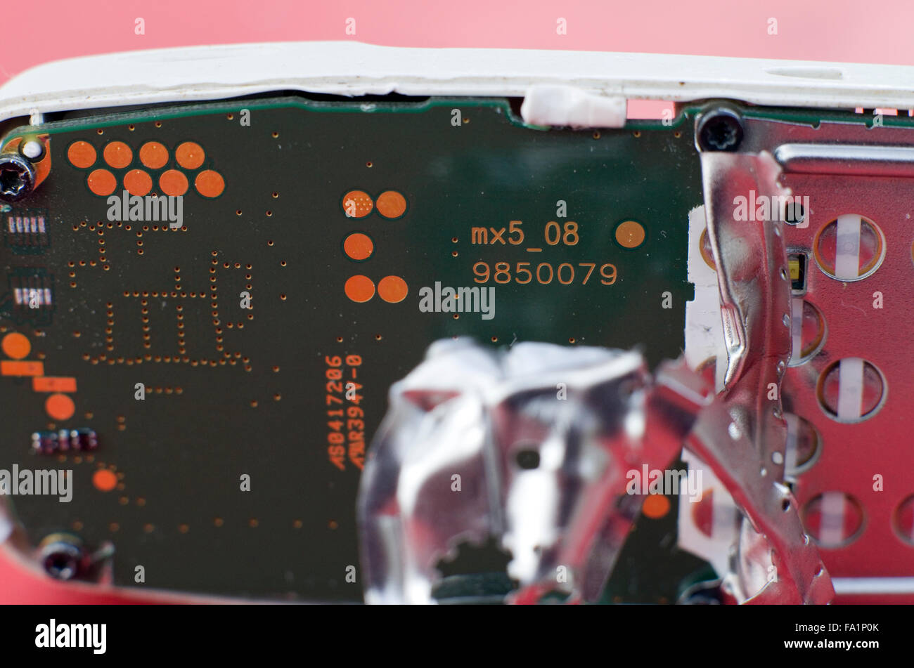 A pile of broken pieces of mobile phones and phone batteries on a red ...