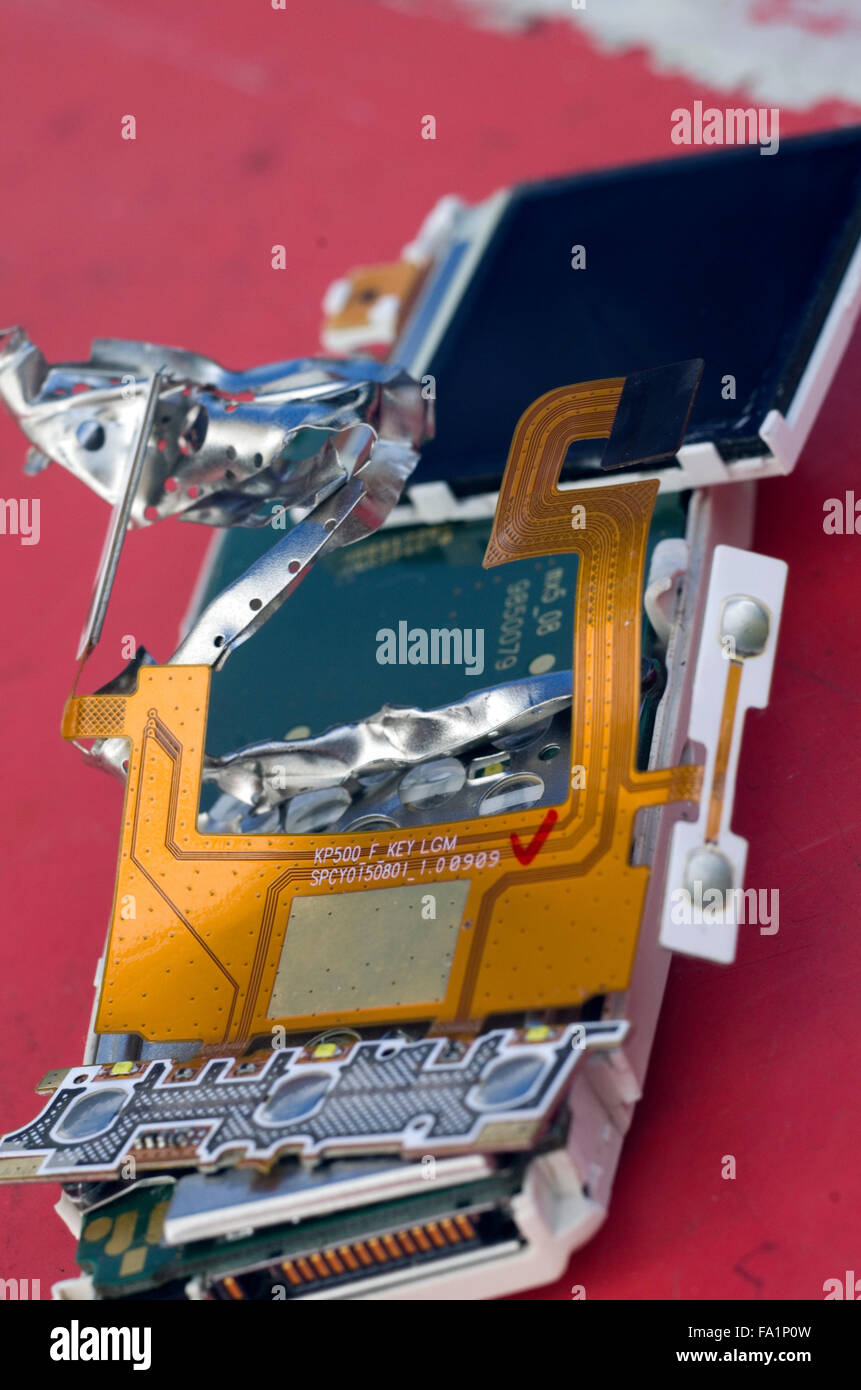 A pile of broken pieces of mobile phones and phone batteries on a red ...