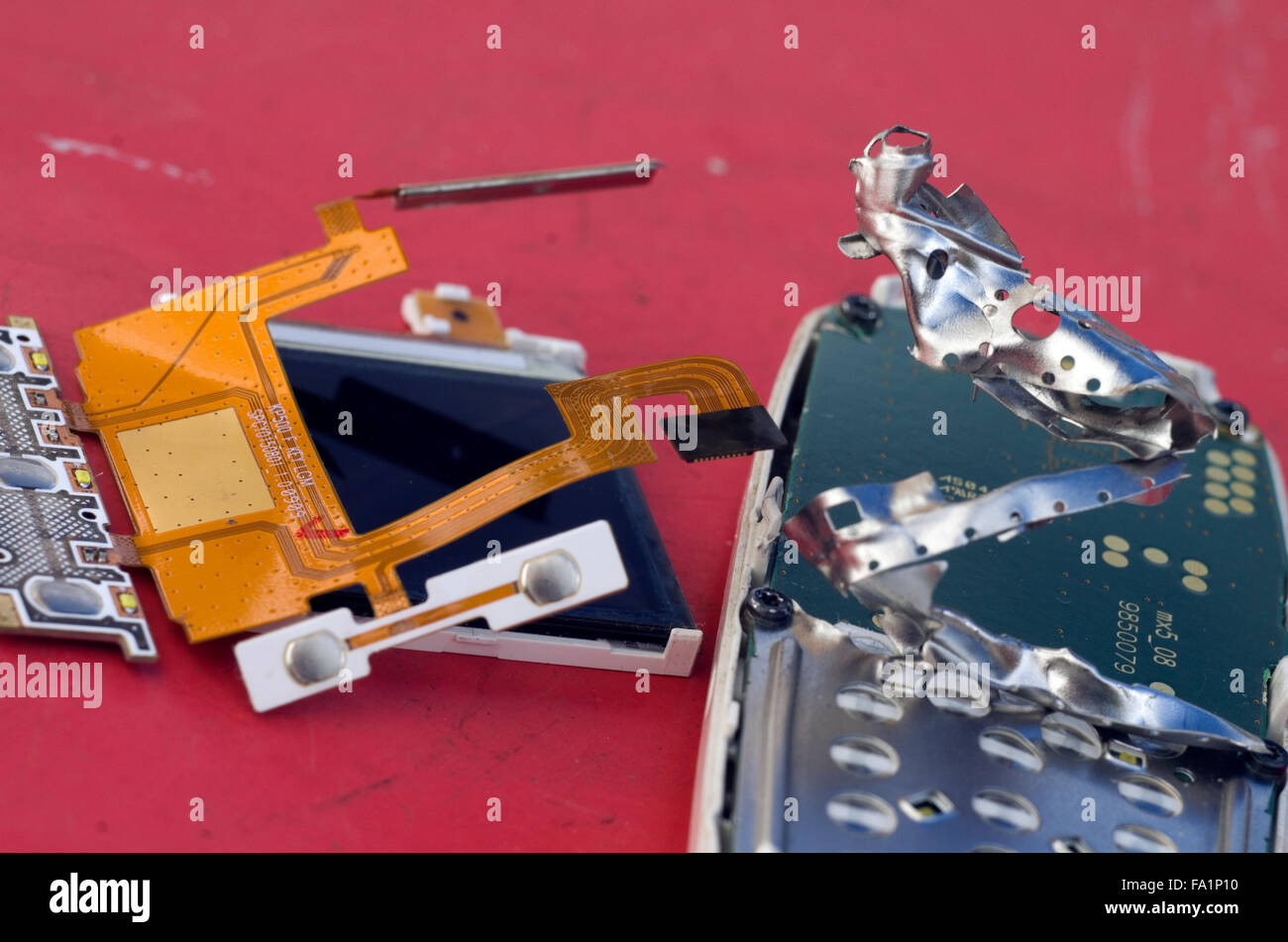 A pile of broken pieces of mobile phones and phone batteries on a red ...