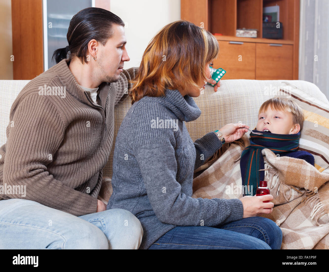 Parents giving medicament to unwell teenager son Stock Photo - Alamy