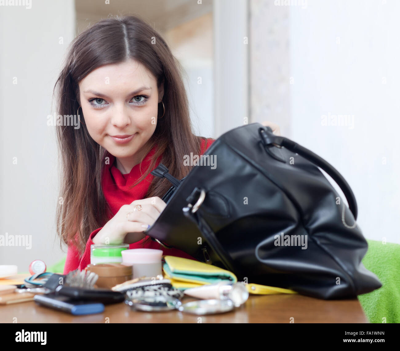 Girl looking for something in her purse at table in home Stock Photo ...