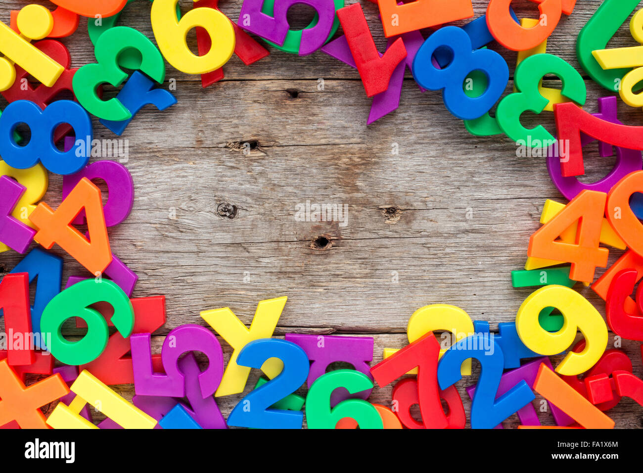 Top border of colorful toy magnetic letters and numbers over a wooden ...