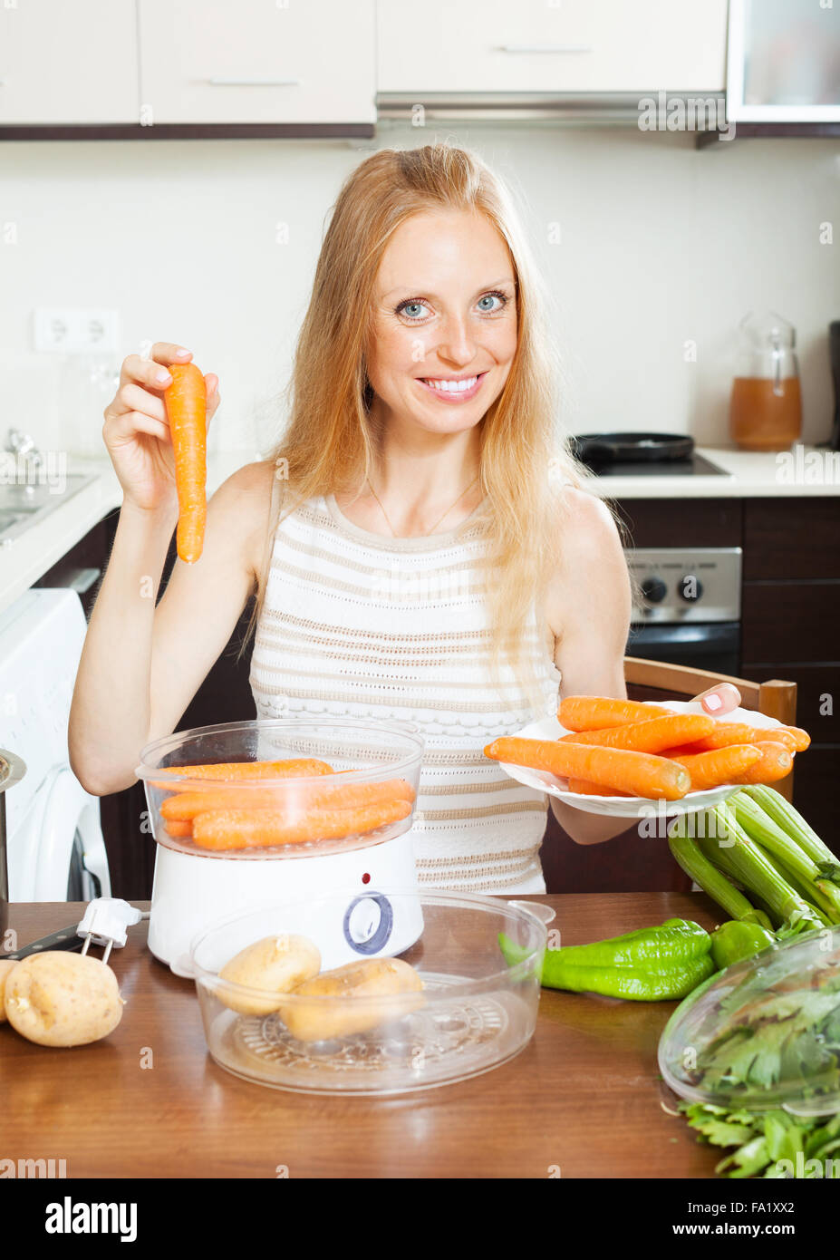 Blonde long-haired housewife cooking vegetables with electric steamer ...