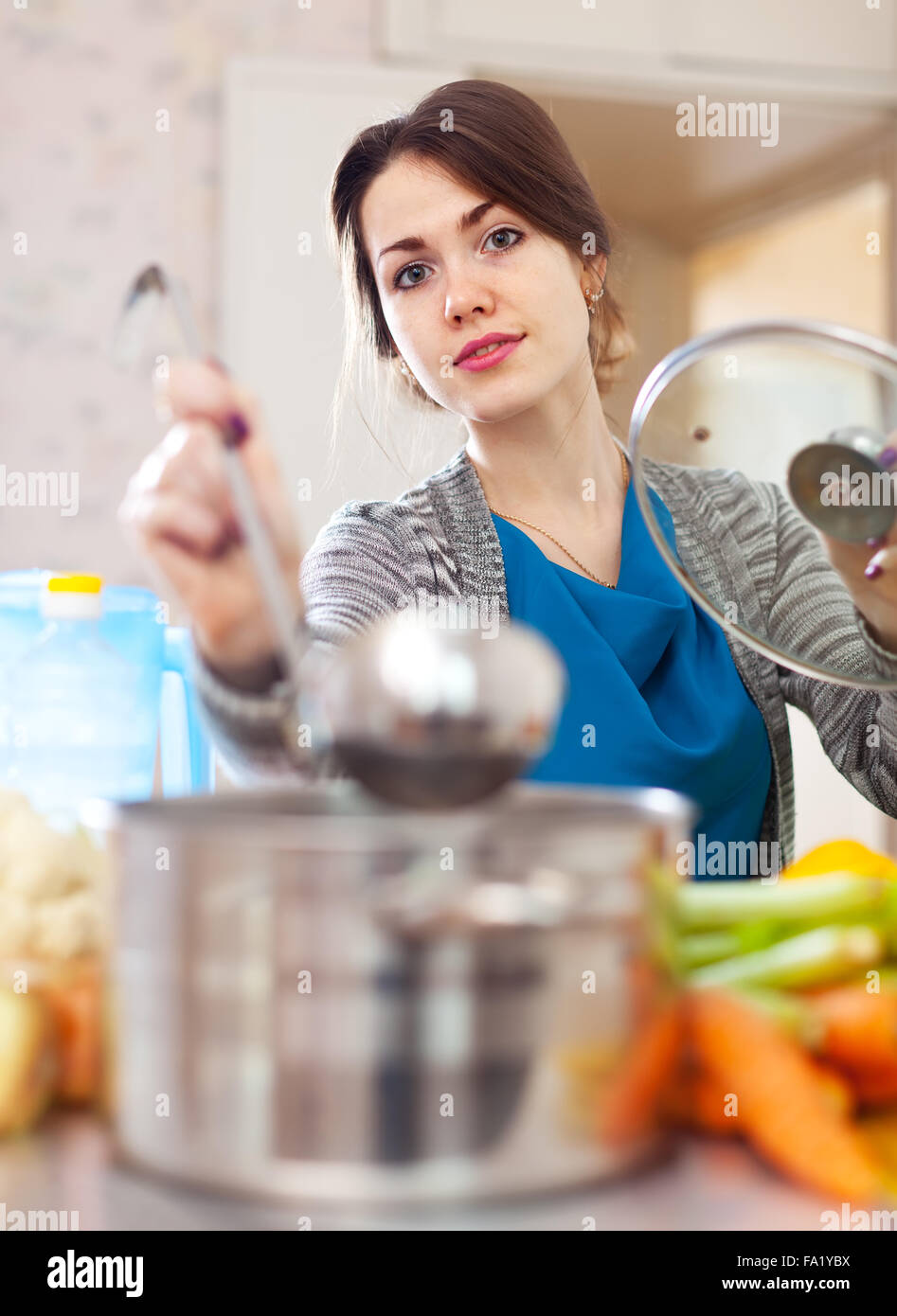 young woman cooking veggie soup with laddle in kitchen at home Stock ...