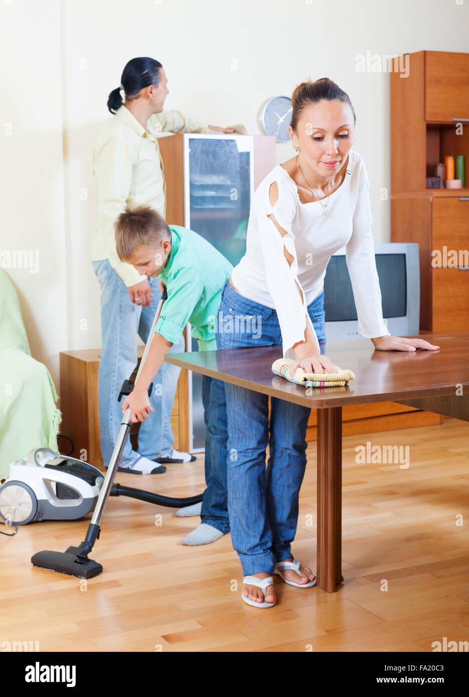 Ordinary family of three doing house cleaning with cleaning equipment ...