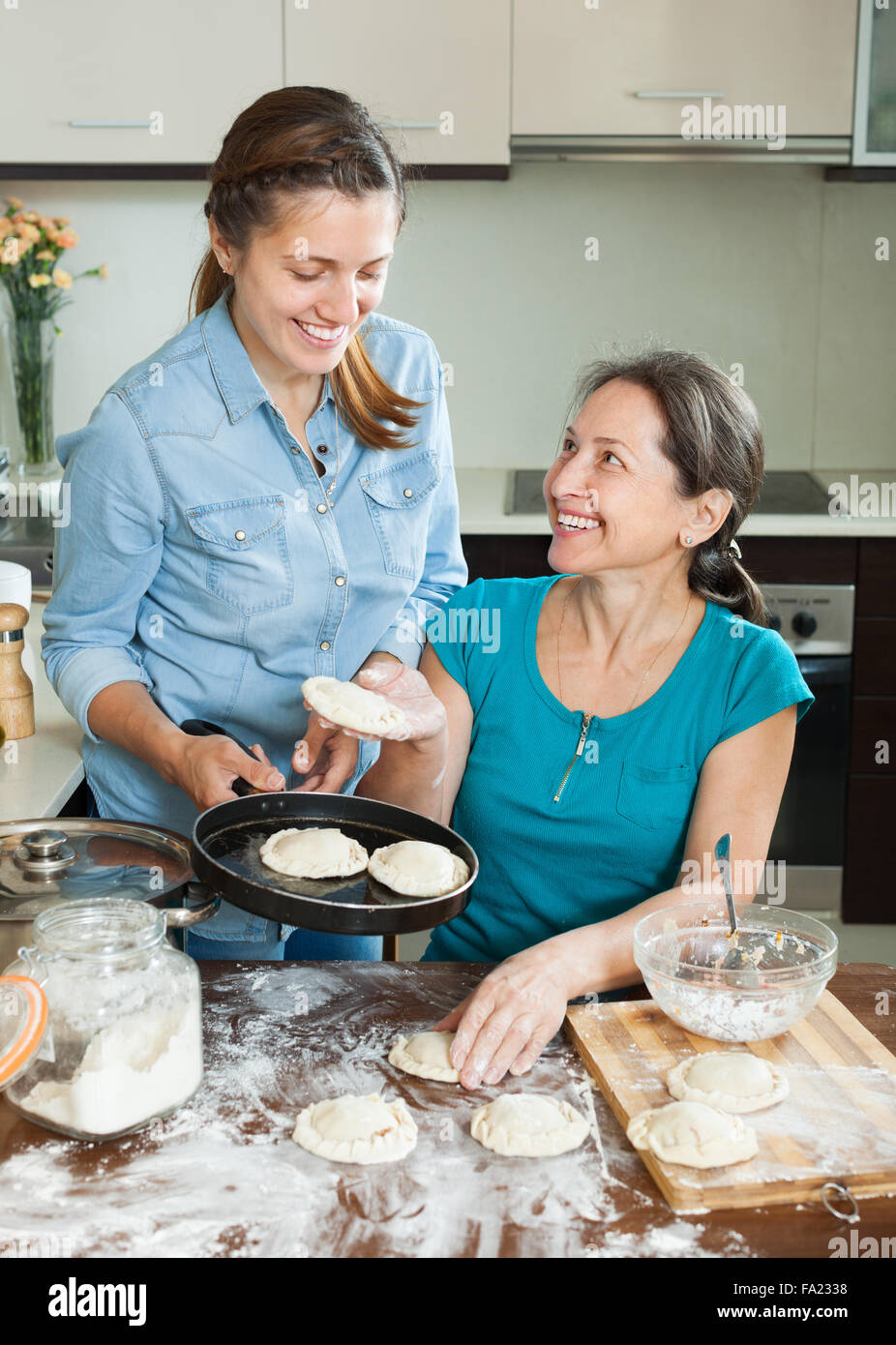 Two laughing women making pies at home kitchen Stock Photo - Alamy