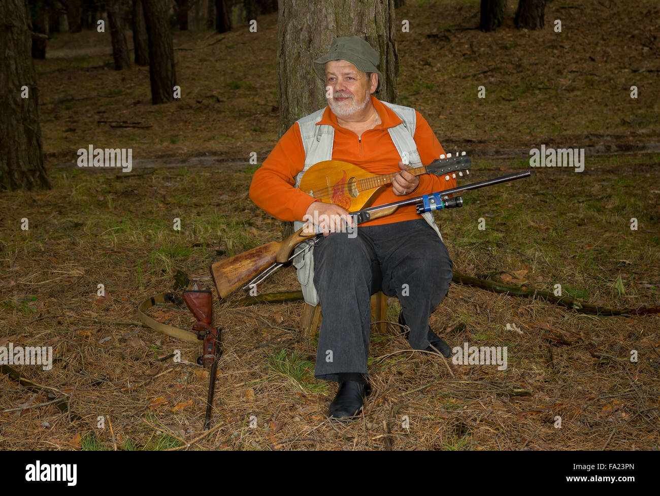 Outdoor portrait of smiling senior hunter resting in evening forest ...