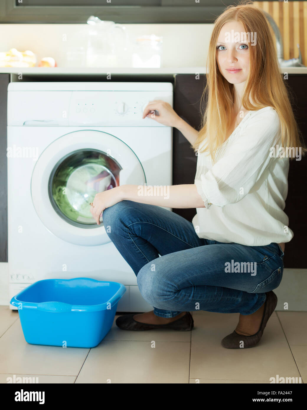 Home laundry. Blonde woman using washing machine at home Stock Photo ...