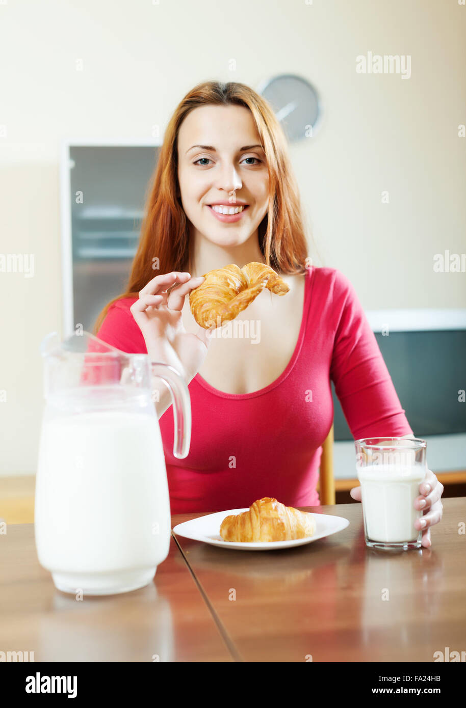 Positive red-haired woman having breakfast with croissants in morning ...
