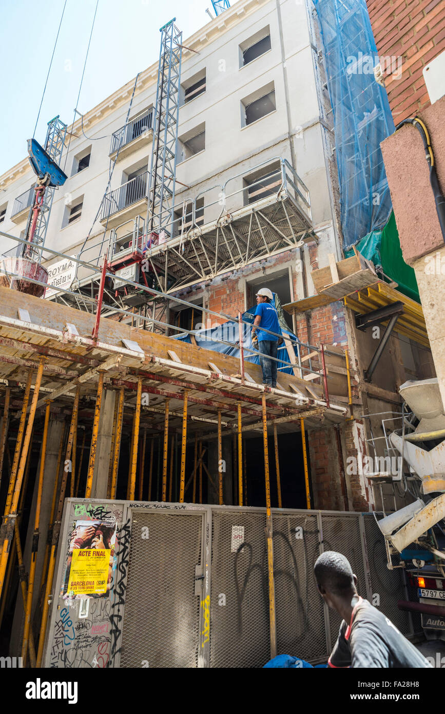Worker running a construction crane is lifting a container of cement in ...