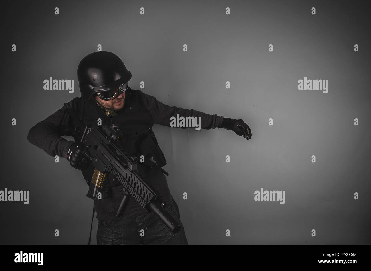 uniform airsoft player with gun, helmet and bulletproof vest on gray ...