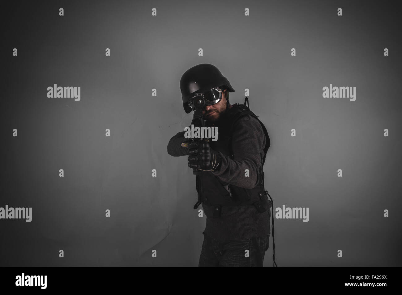 uniform airsoft player with gun, helmet and bulletproof vest on gray ...