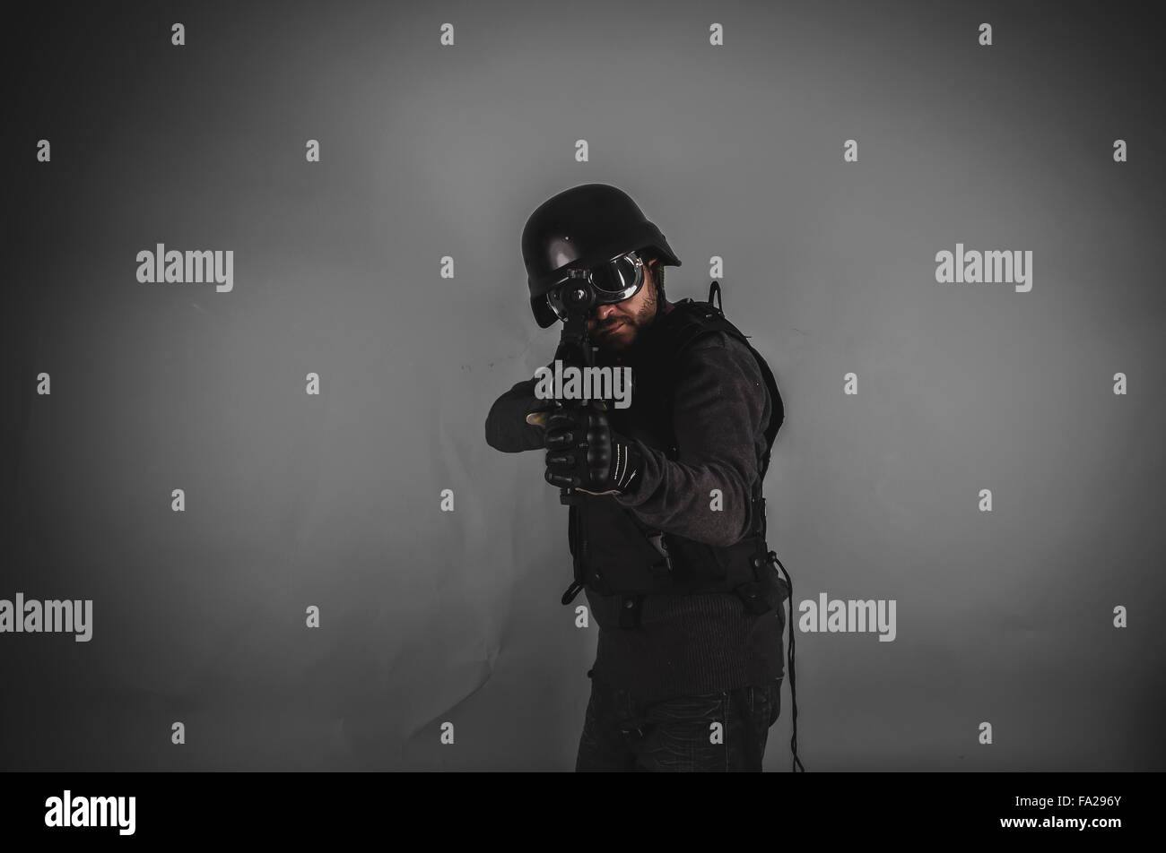 airsoft player with gun, helmet and bulletproof vest on gray background ...