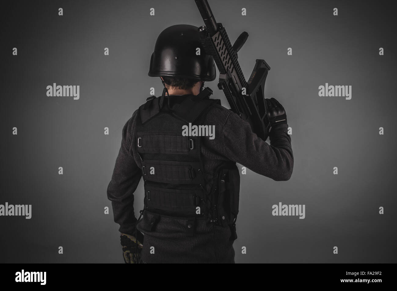 airsoft player with gun, helmet and bulletproof vest on gray background ...